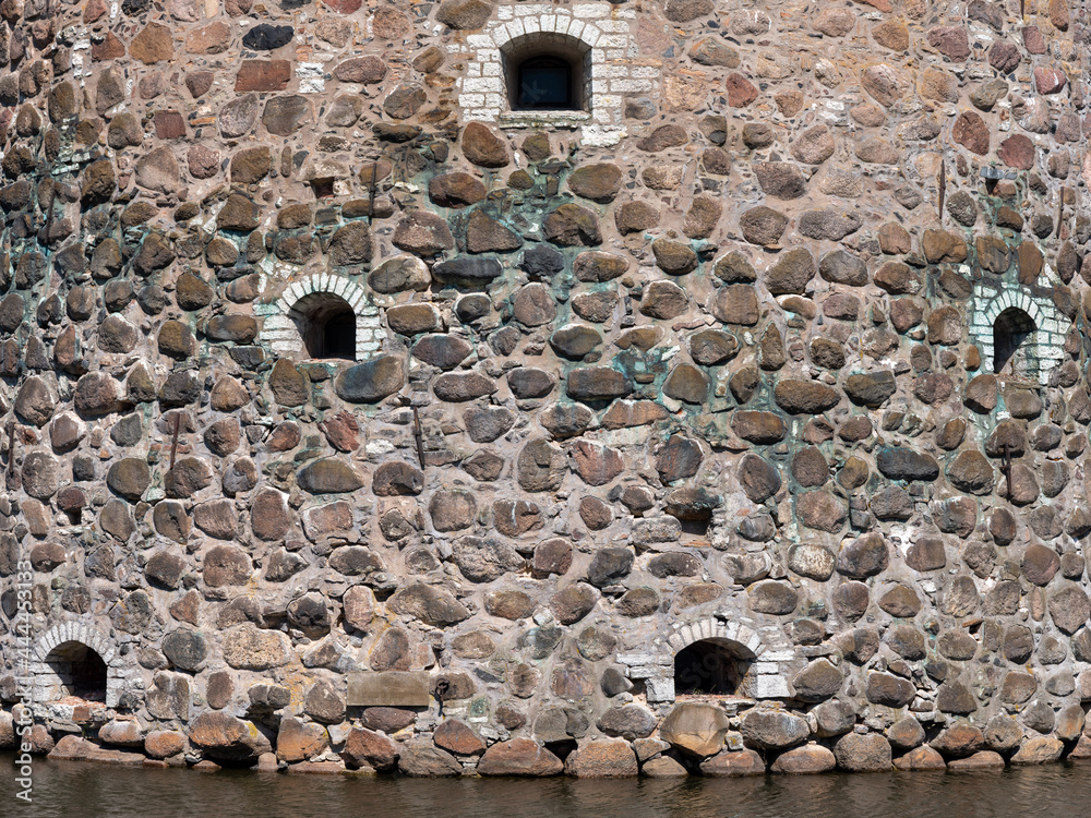 Medieval stone wall with small windows. Water in a mote is visible ...