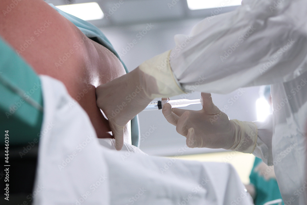 The anesthesiologist performs an epidural anesthesia on the patient's ...