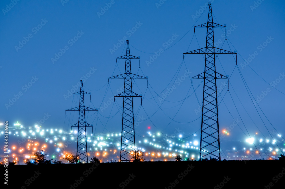 power lines in the evening on the background of blurred city lights ...