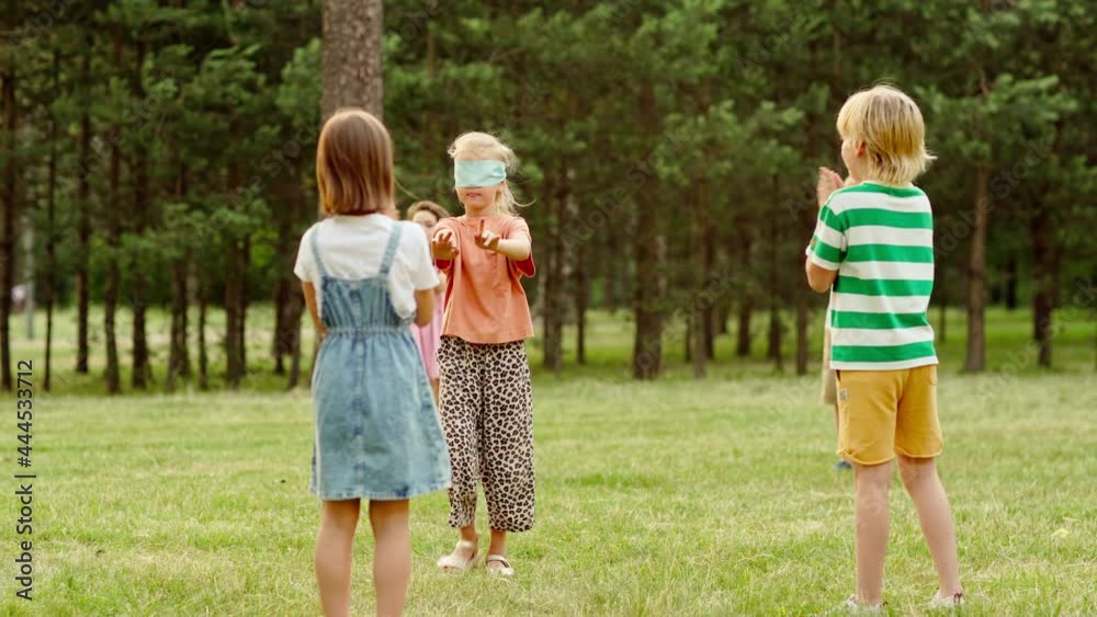 Group of kids playing blind man's buff tag game in park. Blindfolded ...
