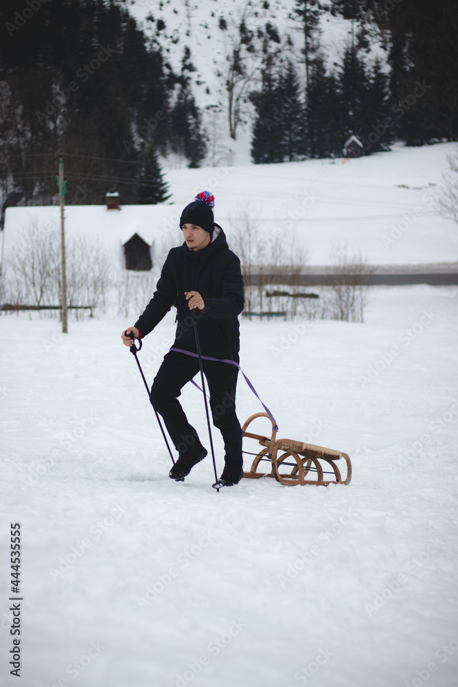 Hiker pulls to the top of a wooden sled for a ride on the piste. Going ...