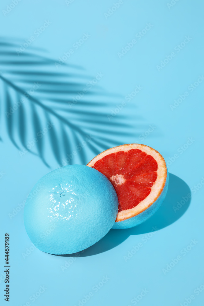 Red grapefruit cut into halves and colored in blue isolated on a light ...