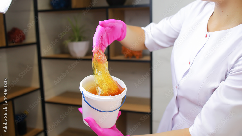 a close-up of the master of sugar hair removal holds a bucket of sugar ...