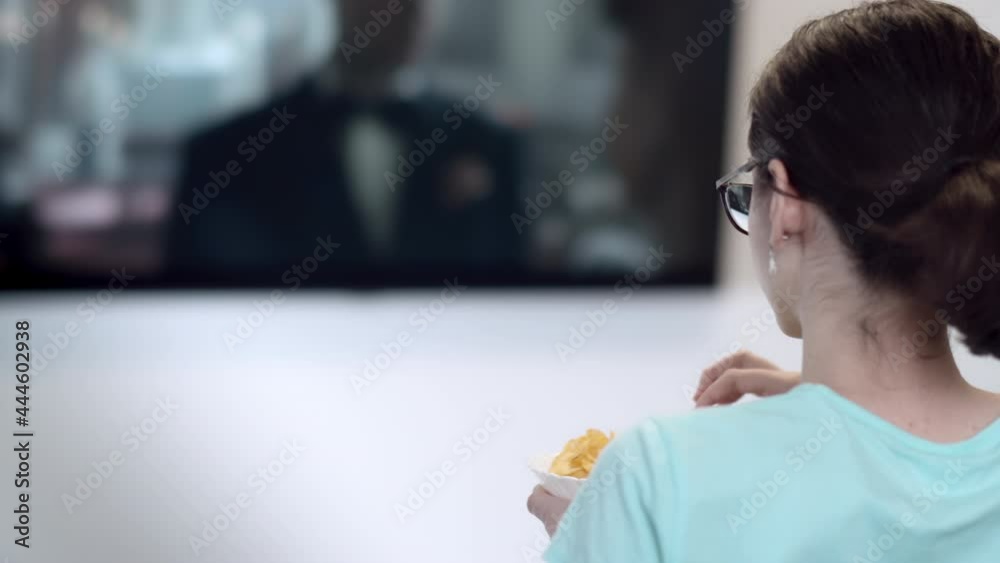 young girl watching tv and eating chips at home, brunette girl watching ...