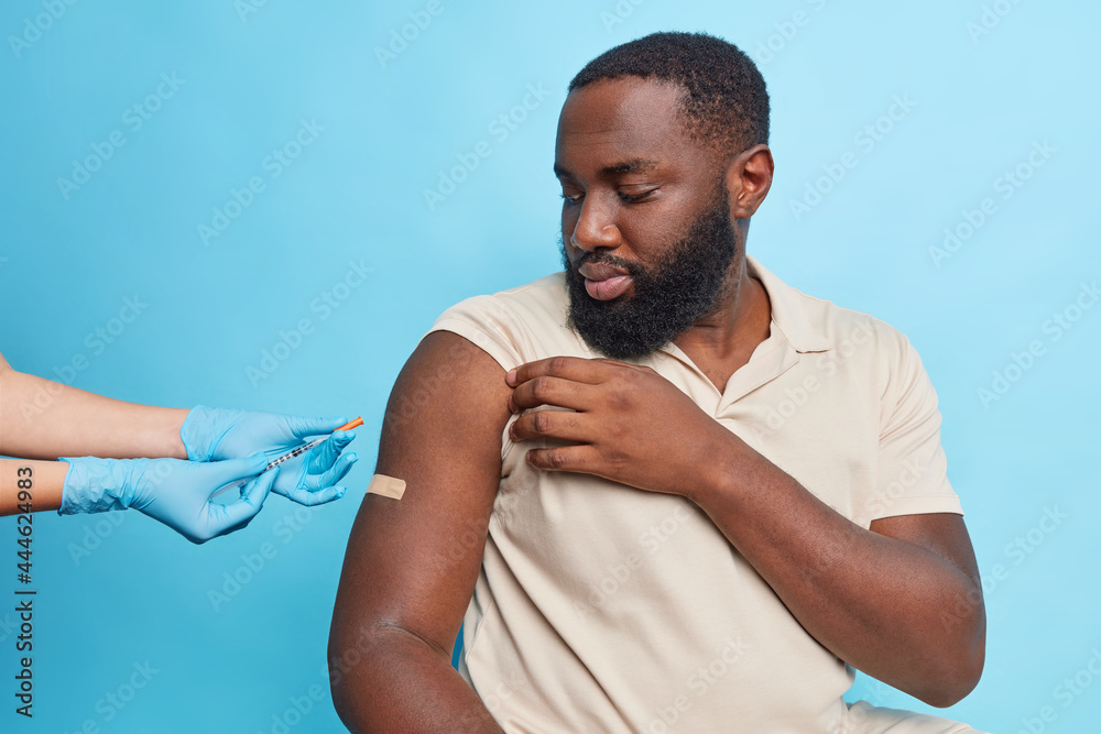 Nurse does injection to man in clinic. Dark skinned man with thick ...