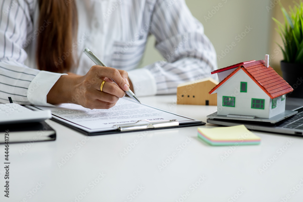 Close up of house model with business woman signs a purchase contract ...