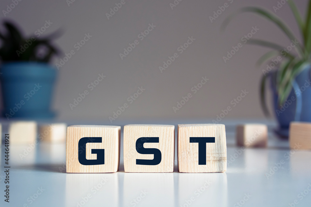 Motivational words: GST in 3d wooden alphabet letters on a blue ...