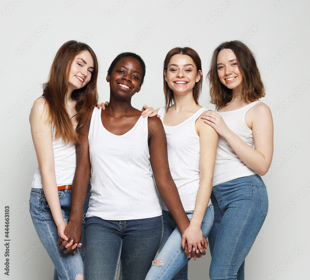 Portrait of four smiling beautiful women in jeans standing together ...