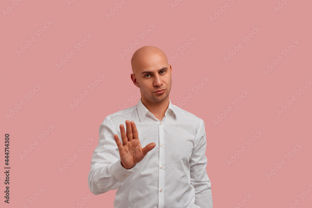 Do not do this. Serious bald man with bristle keeps palm in stop ...