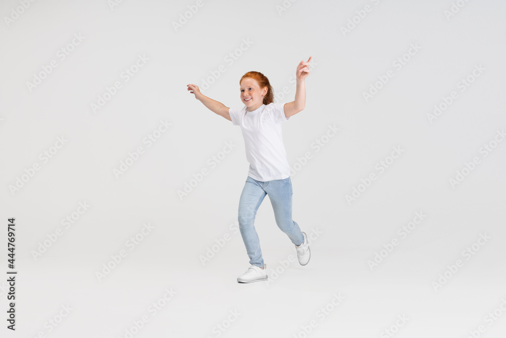 Beautiful cute little red-headed girl in casual outfit running. playing ...