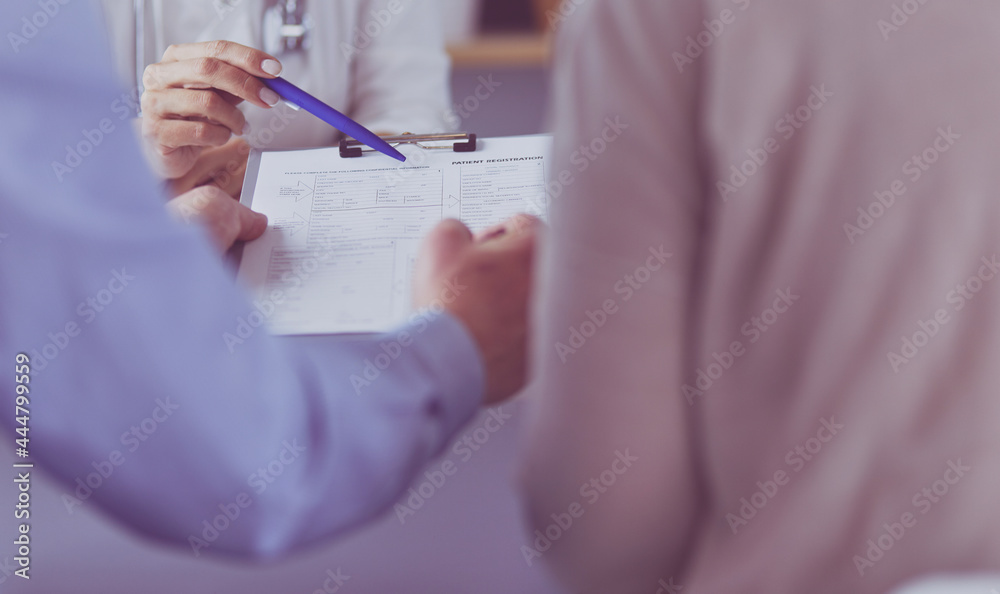 Doctor and patient examining a file with medical records, she is ...