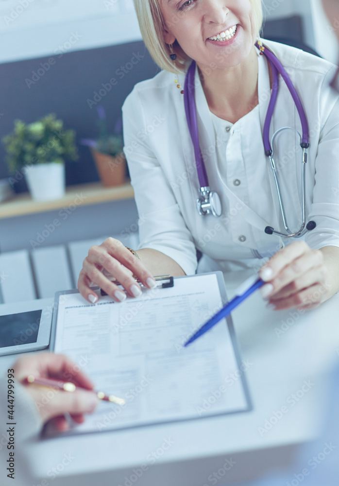 Doctor and patient examining a file with medical records, she is ...
