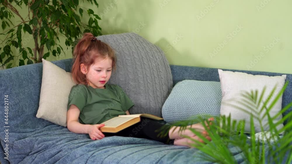 Vídeo do Stock: Little cute girl read paper book on sofa. Preschool ...