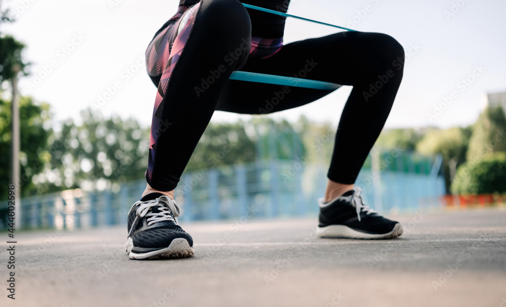 Young girl woman exercising outdoors with mini rubber elastic and doing ...