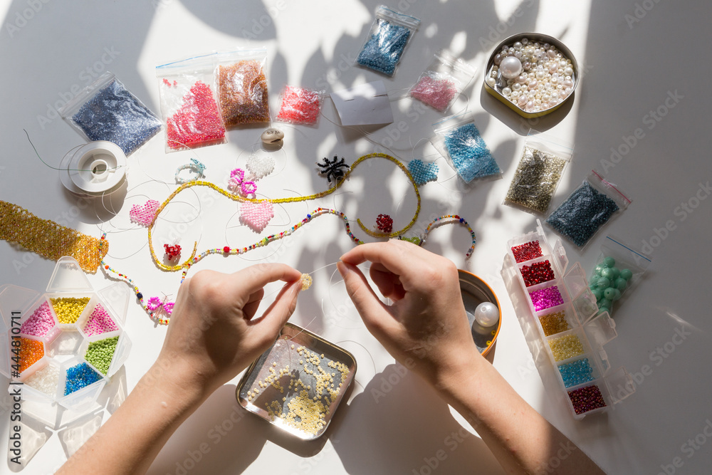 Beading workplace with hands in the process of handicraft. Beautiful ...