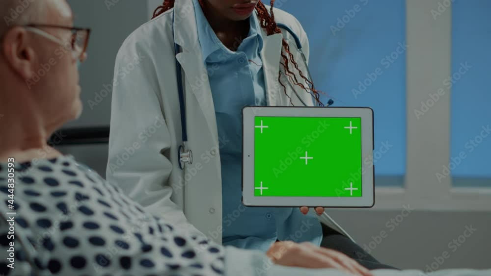Medical practitioner revealing green screen on tablet in hospital ward ...