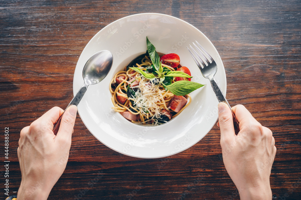 Table top view of woman trying to eat Spaghetti with knife and fork ...