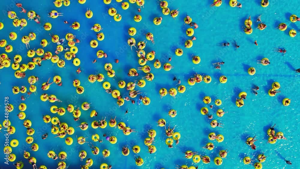 Public pool, water park, people in the pool on yellow swimming rings ...