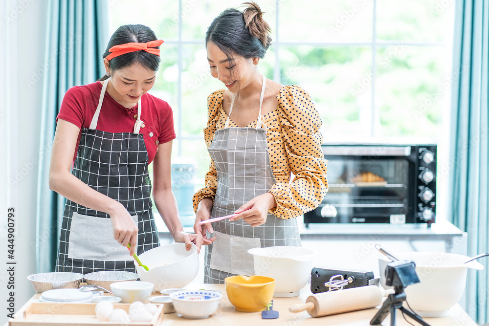 Two girlfriends make a bakery together and bake cream pies on a tray ...