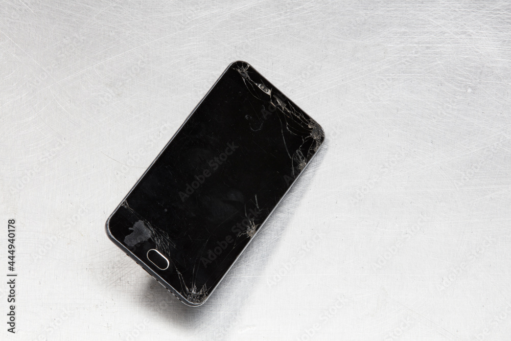 Broken and scratched smartphone on a metal background. Black broken ...