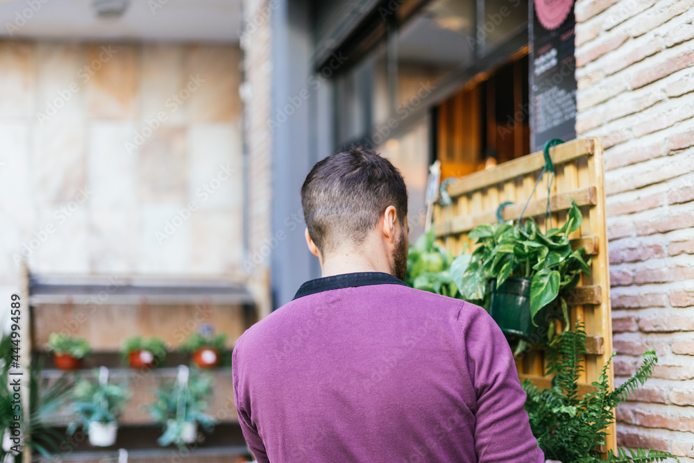 Sales clerk with her back to the store placing flower pots in her store ...