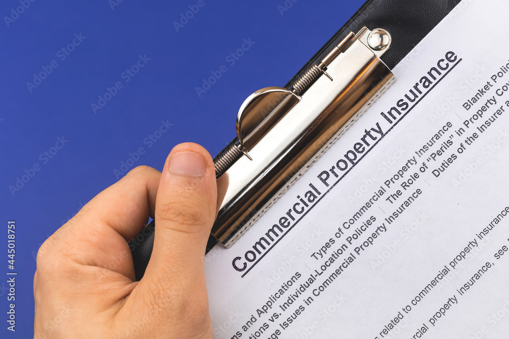 Man hold commercial property insurance claim form and policy in hand ...