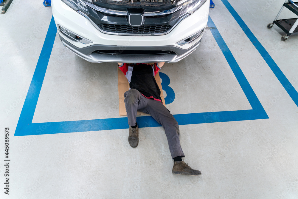 Top view of mechanic in uniform lying down and working under car, car ...
