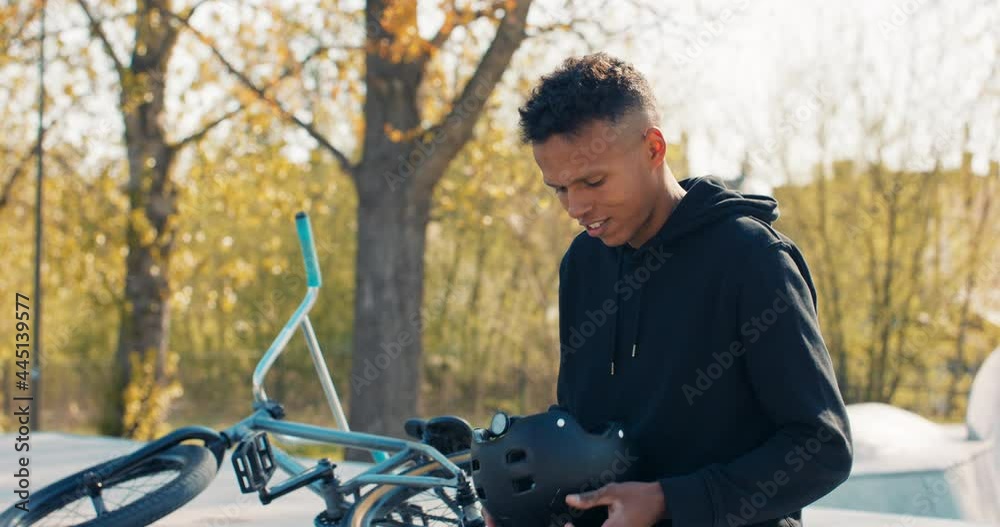 Cyclist who fell off bike, a bmx, and is sitting on a concrete ramp ...
