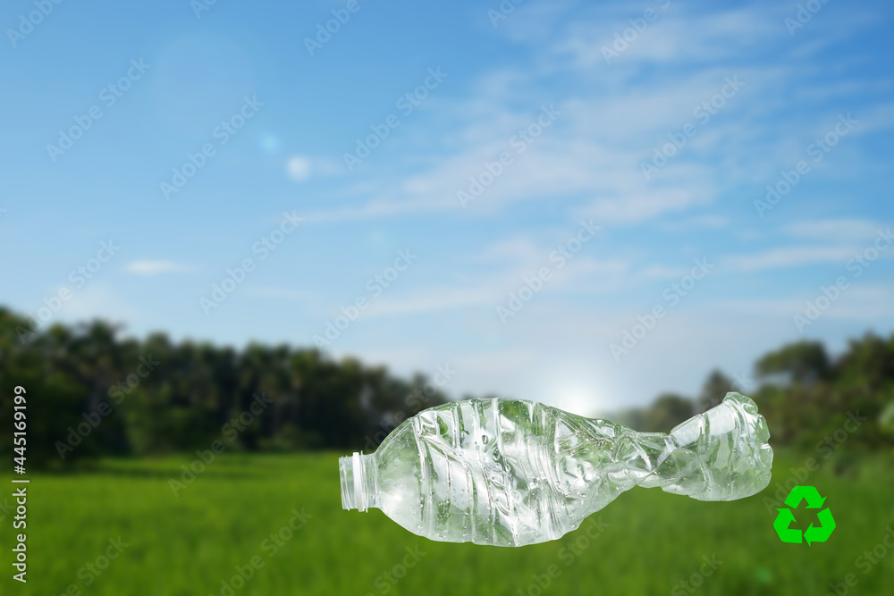a transparent empty plastic bottle is squeezed and recycling symbol ...