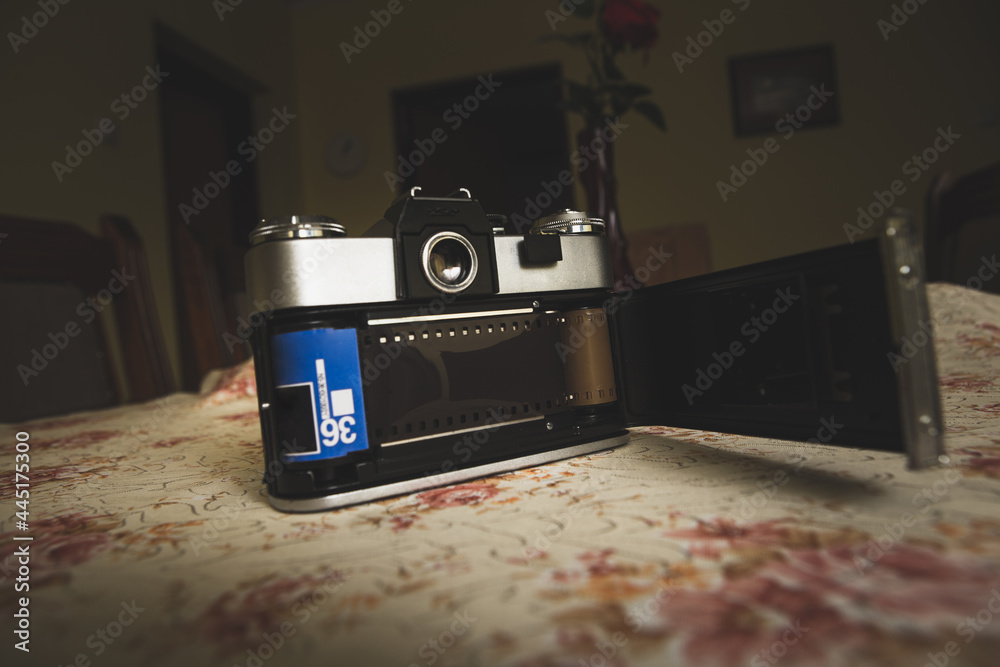 An old analog camera is on the table in the house. The camera is open ...