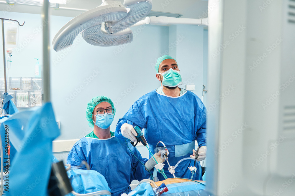 two surgeons in a laparoscopic surgical procedure look at the monitor ...