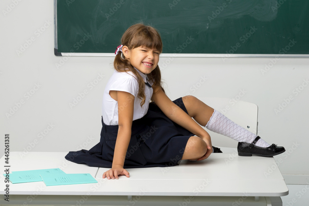 Happy school girl sitting on desk in classroom Stock Photo | Adobe Stock