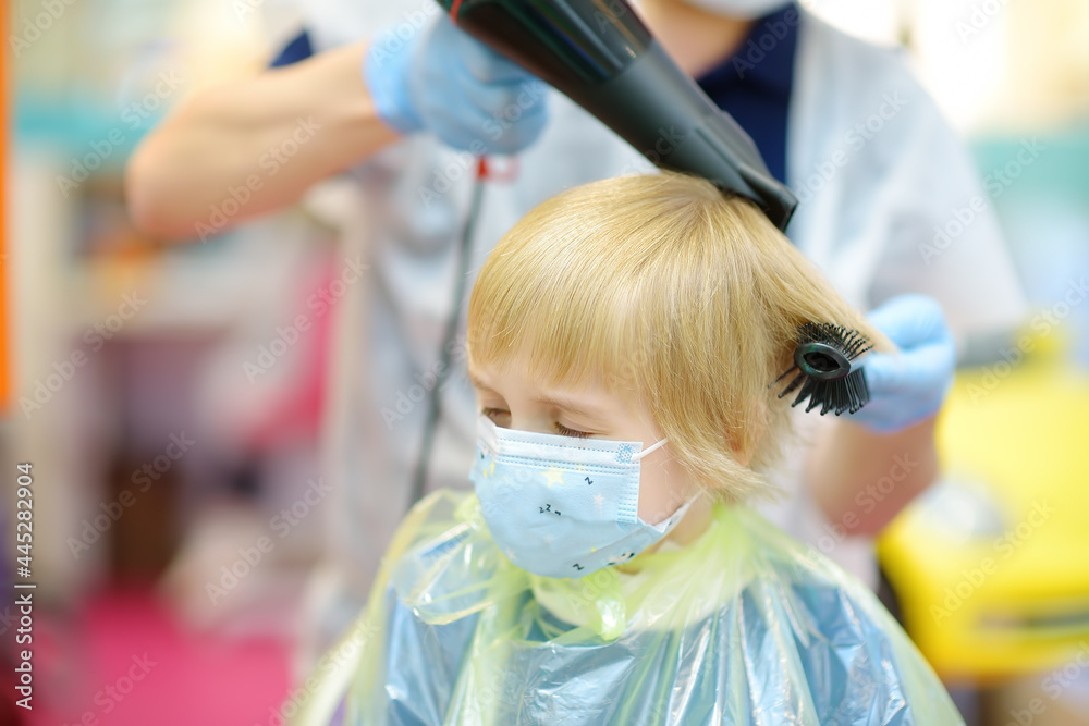 Preschooler boy wearing facemask getting haircut in salon during ...