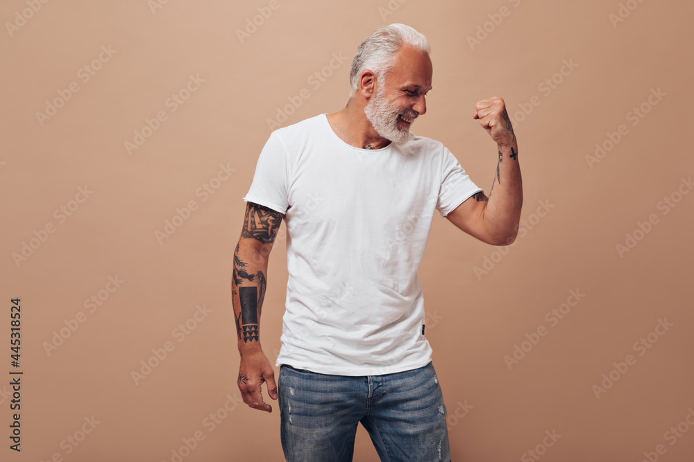 Charming man in jeans and white shirt demonstrates biceps. Attractive ...