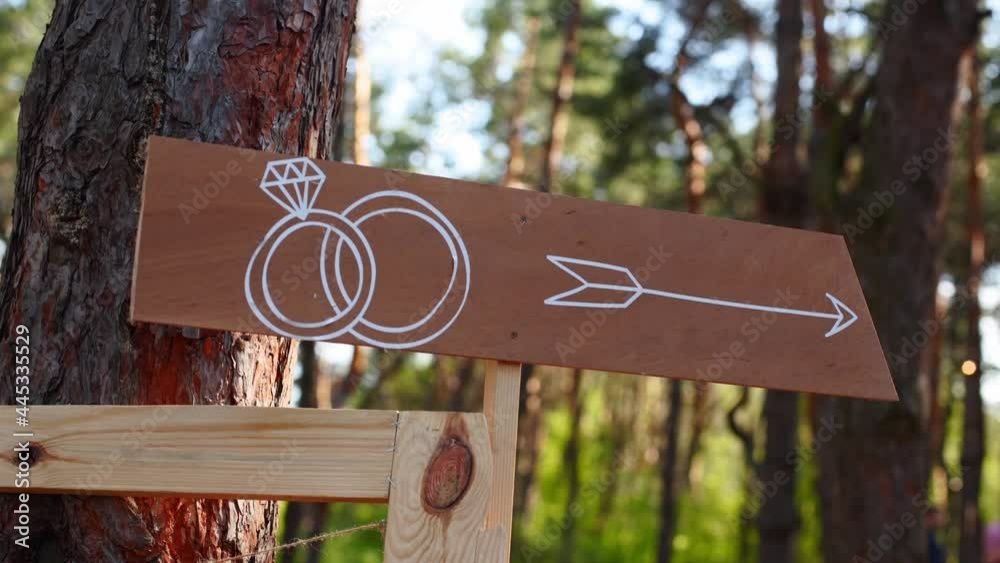 Wooden arrow sign with wedding rings on ceremony venue. Wedding party ...