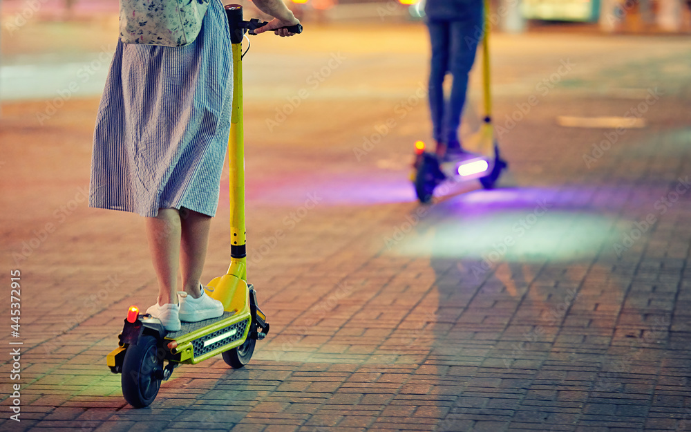 Young couple on electric scooter with headlights drive through city ...
