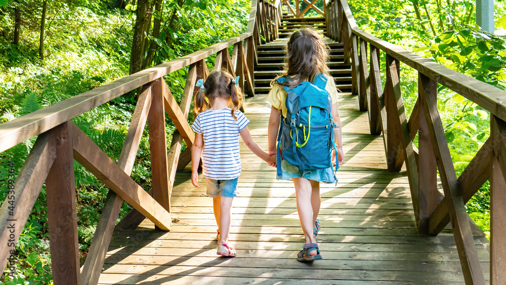 Children with backpacks on their shoulders head to the family camp on a ...
