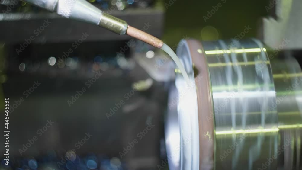 A lathe processes the metal workpiece with coolant which cool the tool ...