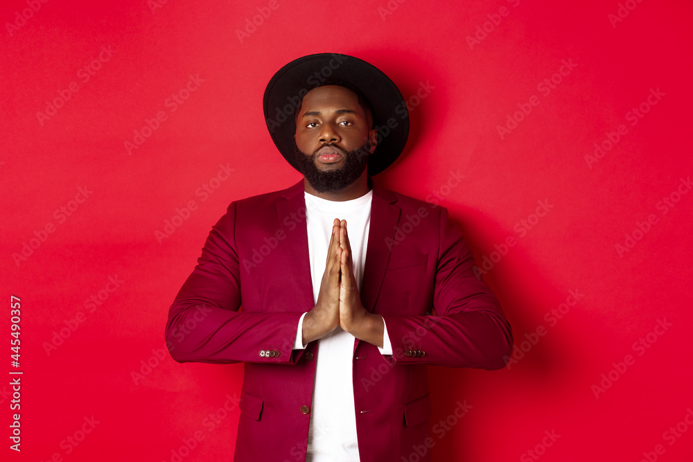 Serious african american man showing respect, holding hands together in ...