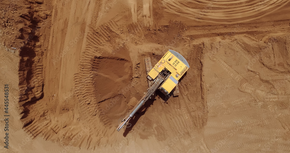 Aerial view of a digger, tracked excavator at work on a construction ...