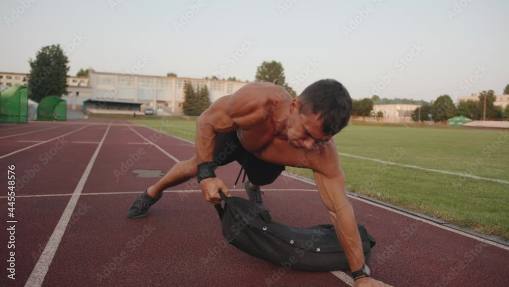Bodybuilder training in the stadium and does core and shoulder strength ...