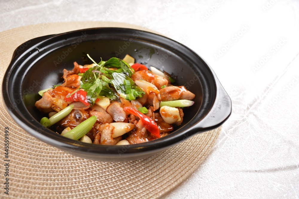 Stir fried spicy mala chicken meat with vegetables in black hot clay ...