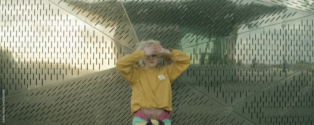 Zoom out anamorphic shot of girl in streetwear looking at camera and ...