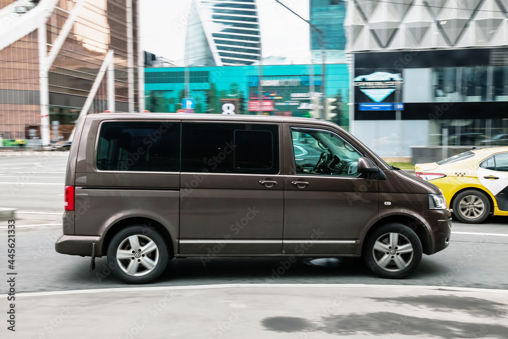 Fast moving Volkswagen Transporter T6 on the city road. Brown van rides ...