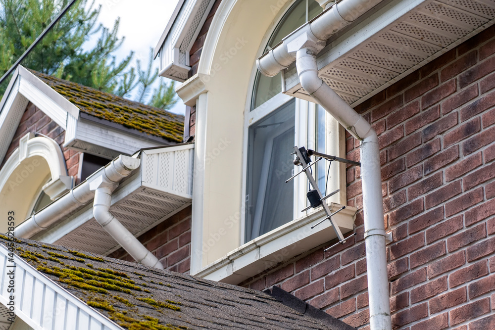 Closeup view of old white gutter system with soffit vent, window with ...