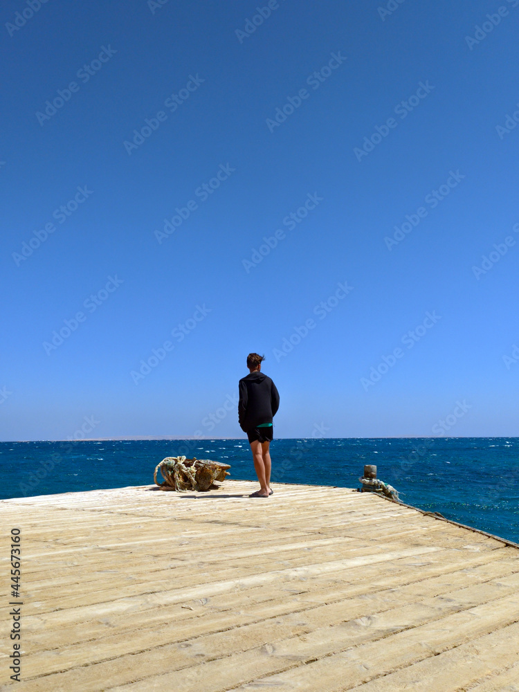 Young man standing alone on edge of footbridge and staring at sea Stock ...