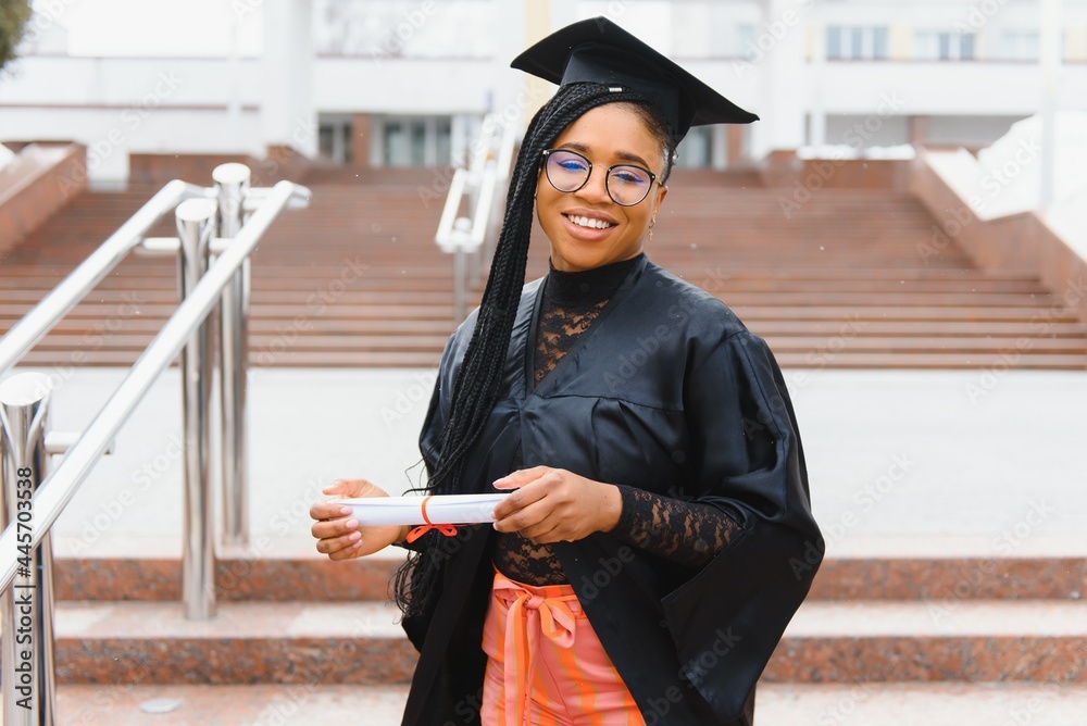 pretty african college student in graduation cap and gown in front of ...