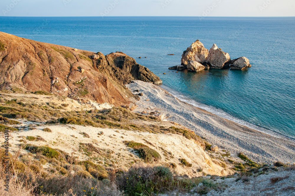 The magical colors of the sunset play on the pebbles of a wide beach ...