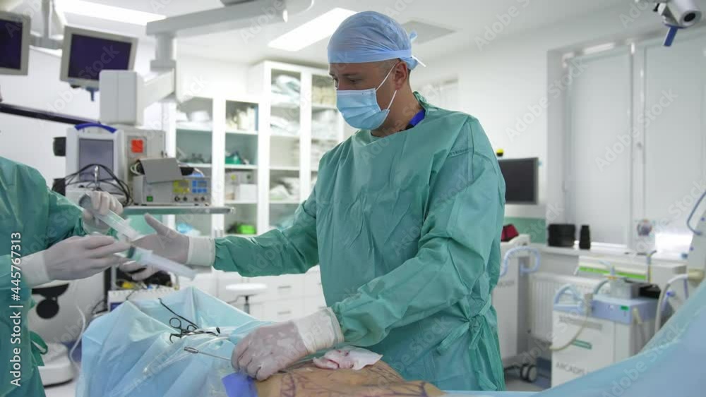 Doctor removes the fat during the liposuction of the patient with ...