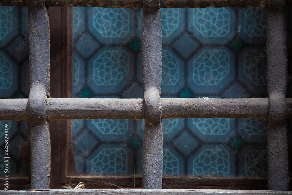 Metal grey ancient grate on the window with blue stained glass ...